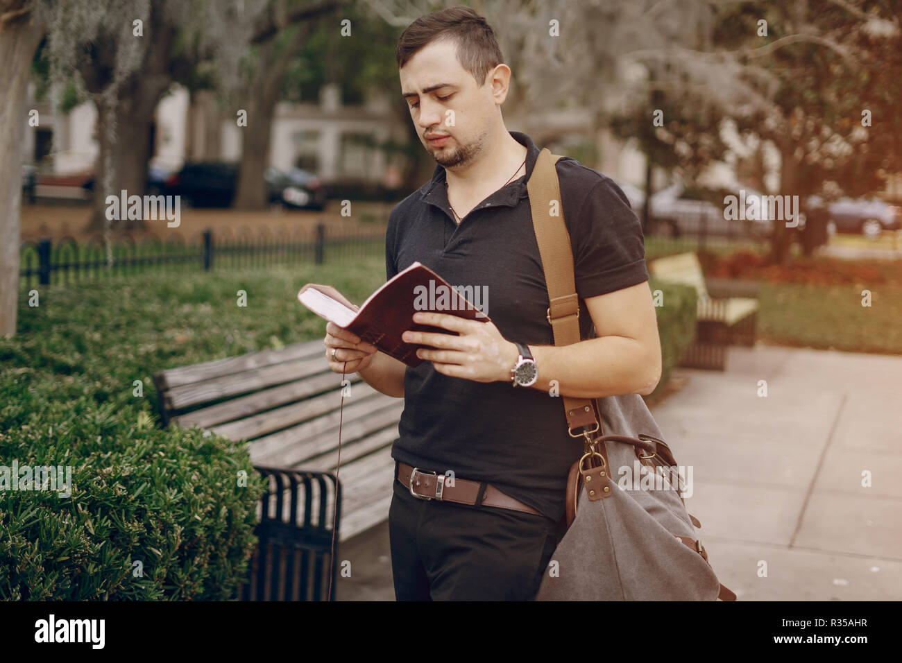 handsome young man is traveling with a notebook and a bag in the city ...