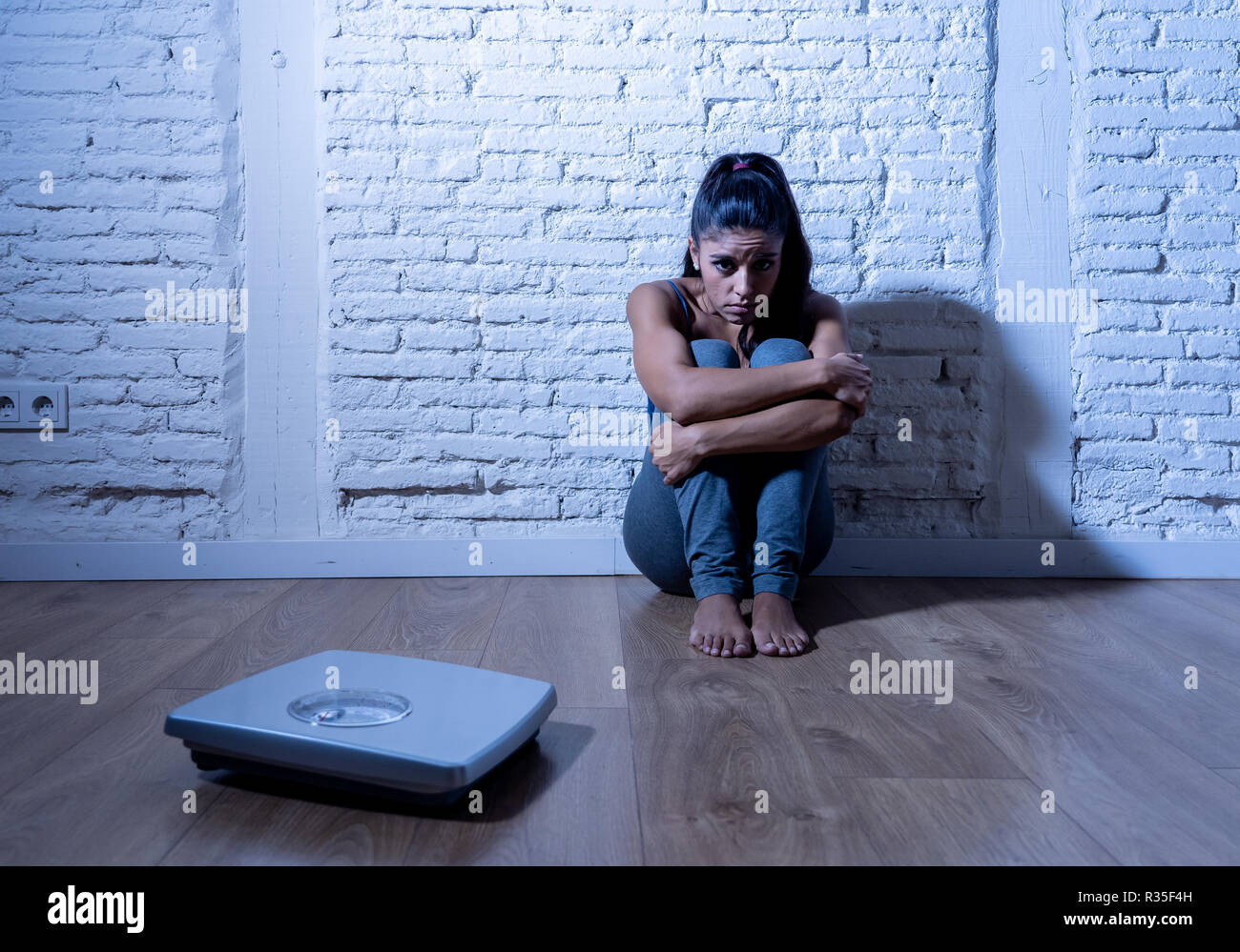 Young anorexic bulimic teenager woman sitting alone on ground looking ...