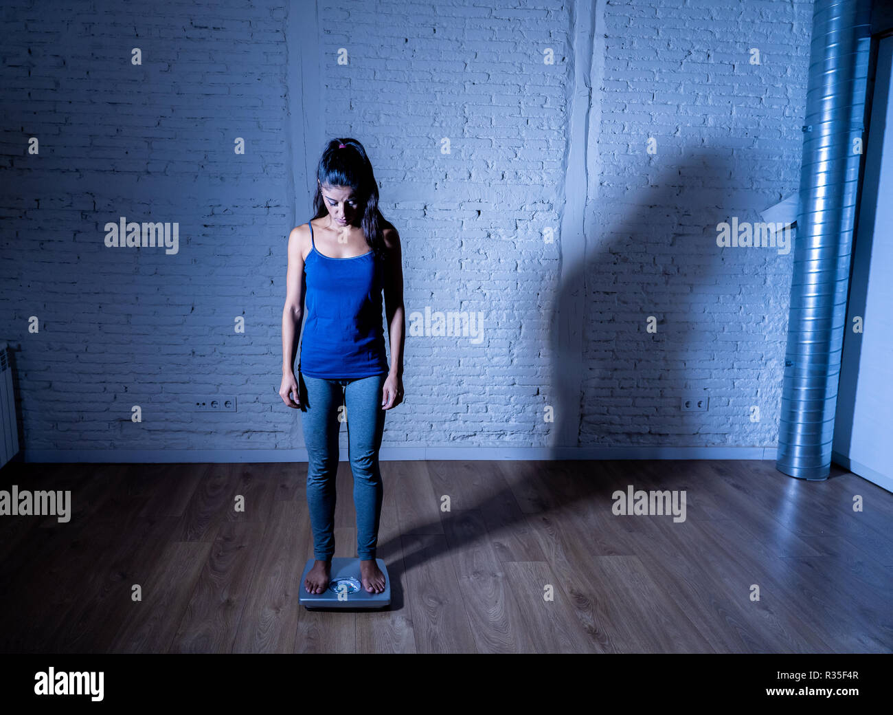 Young fit and slim woman checking body weight on scale finding herself ...