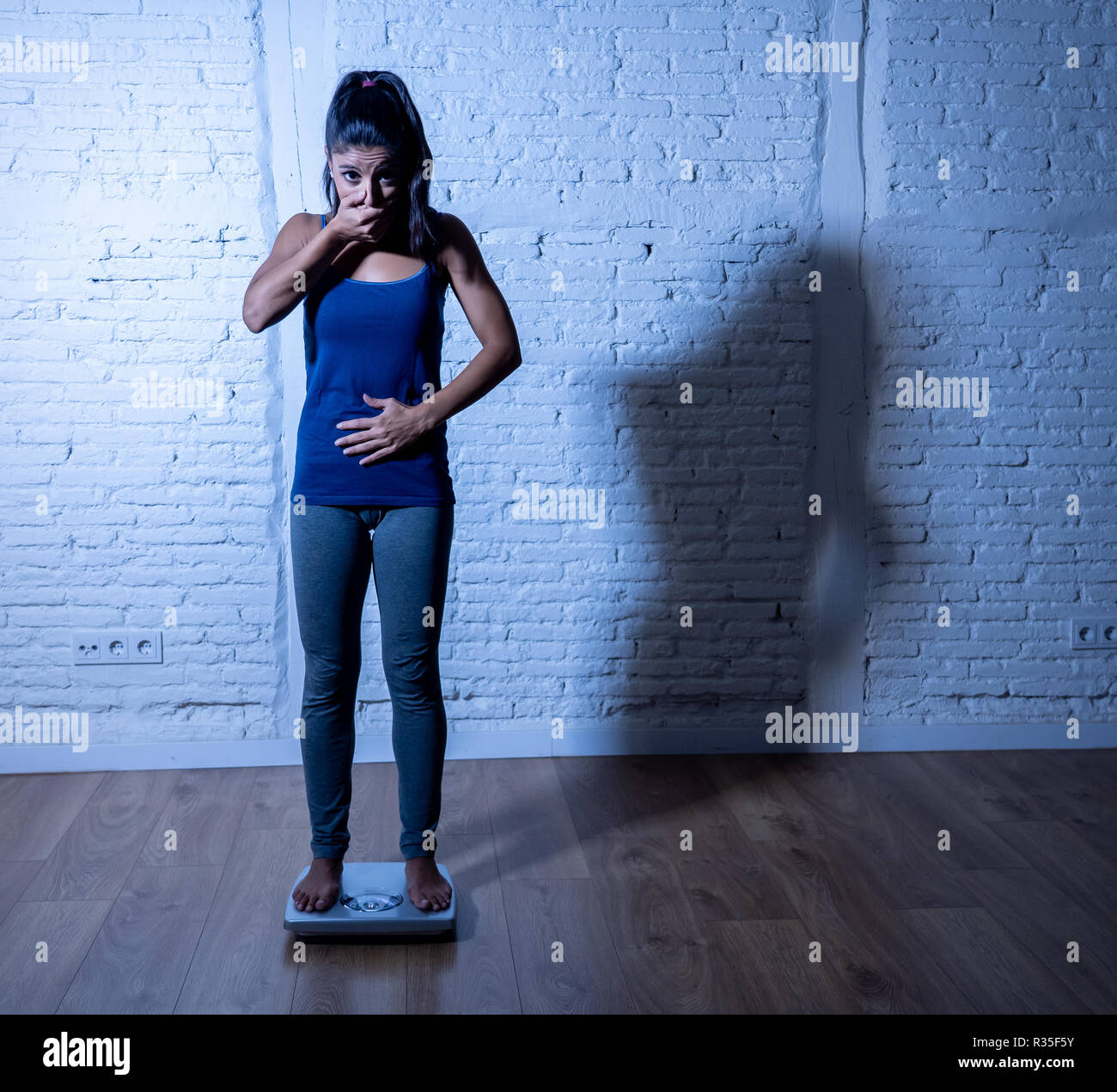 Young fit and slim woman checking body weight on scale finding herself ...