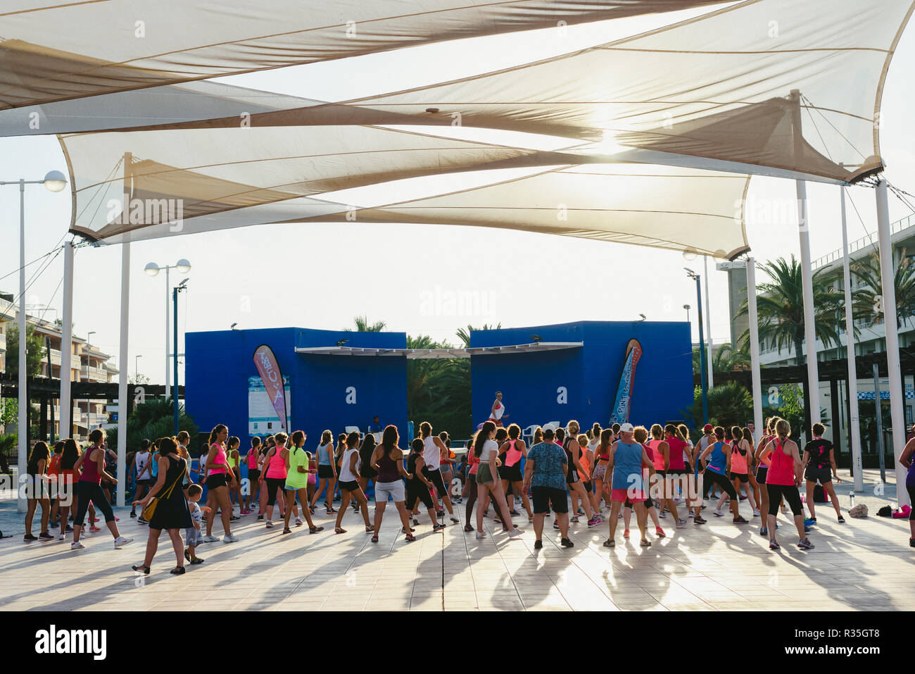 Fitness class and popular outdoor aerobics with monitor on a beach in ...