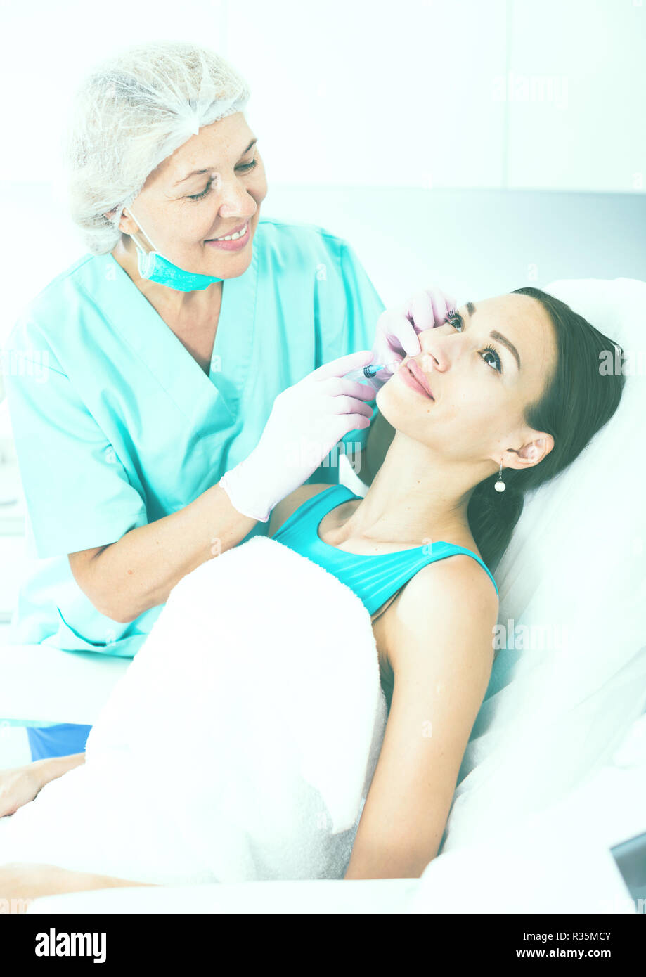 Young woman getting injection for facial correction procedure in ...