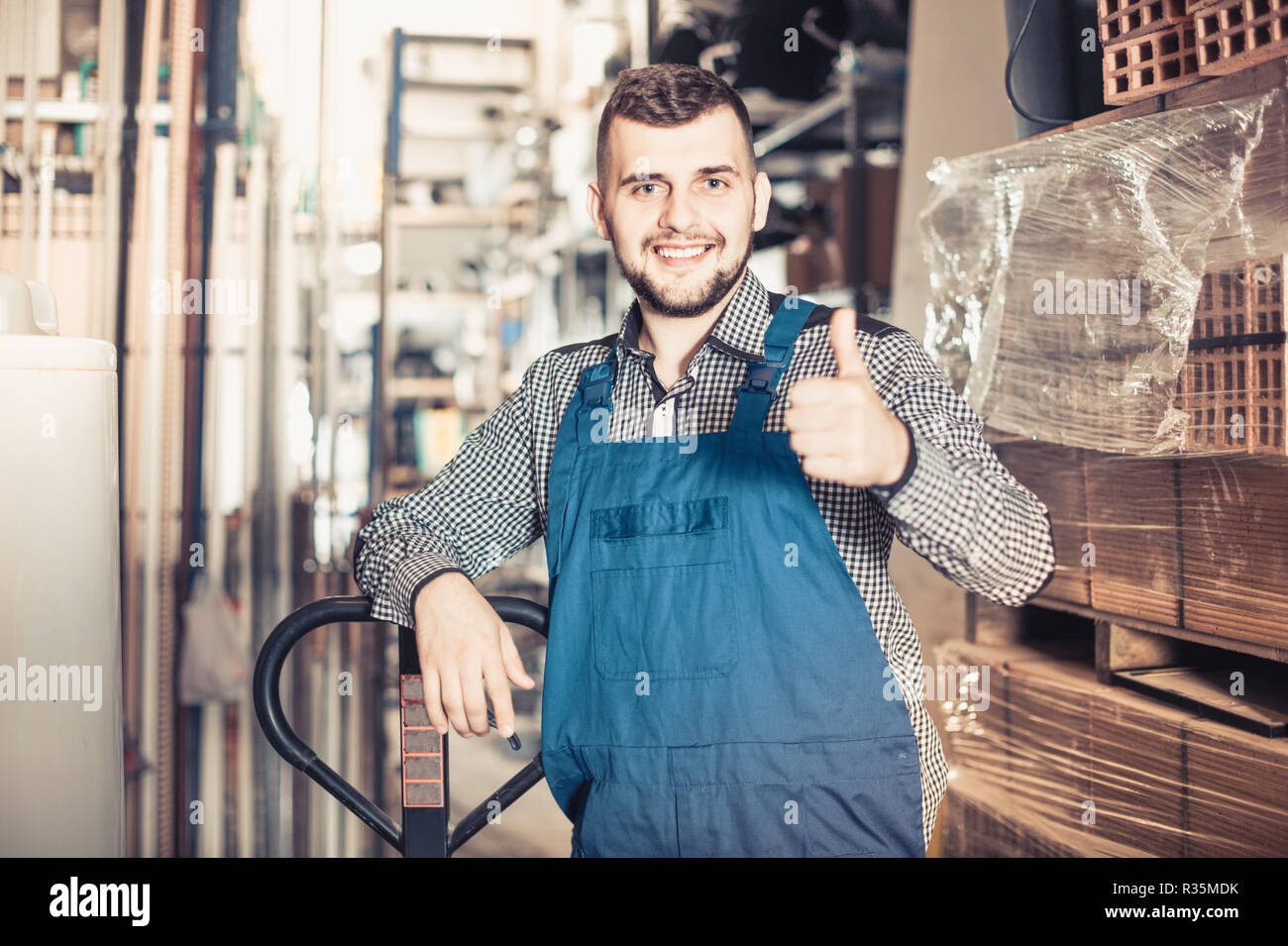 Friendly smiling working man demonstrating his workplace at workshop ...