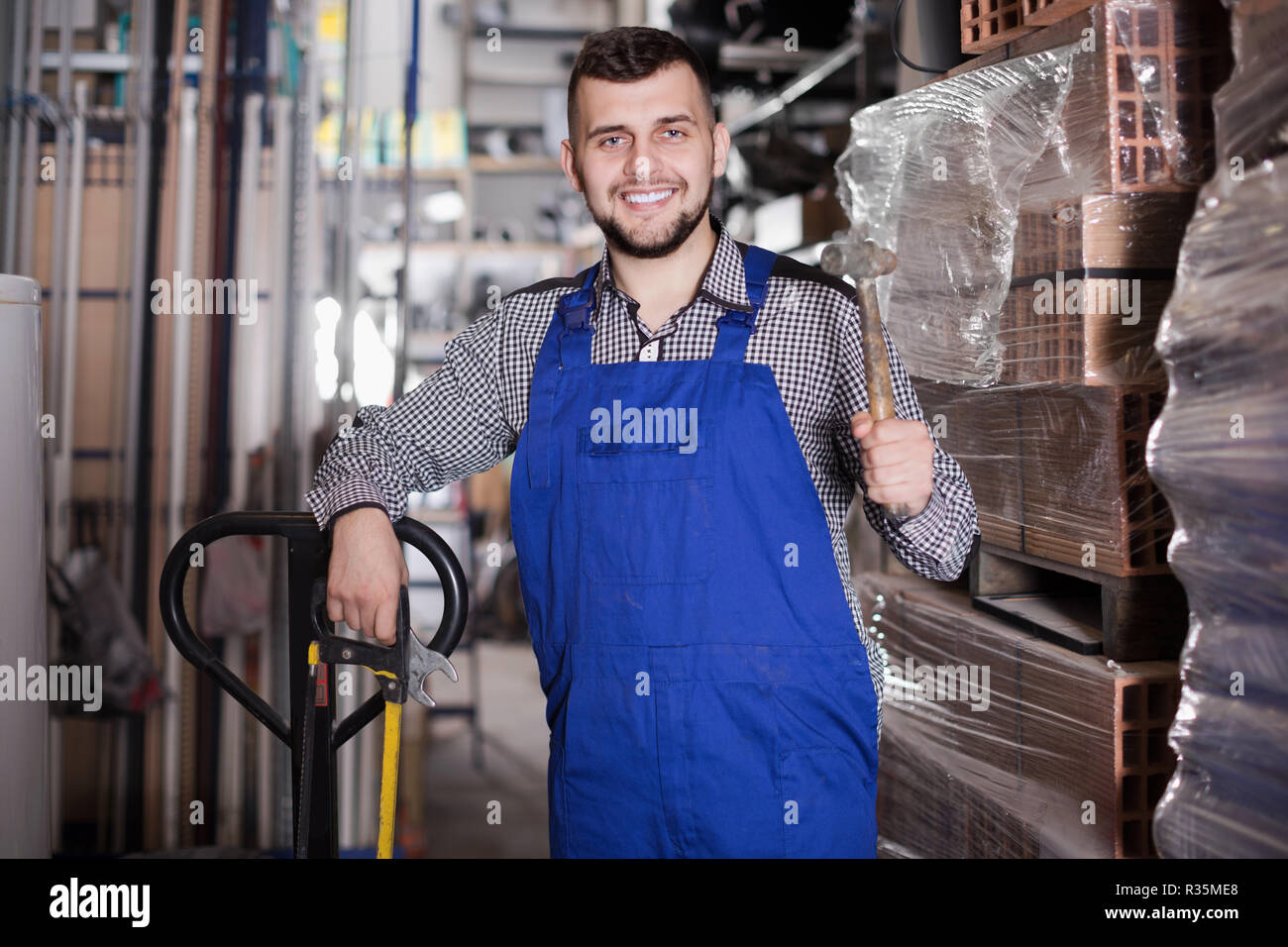 Smiling working male demonstrating various tools at workshop Stock ...