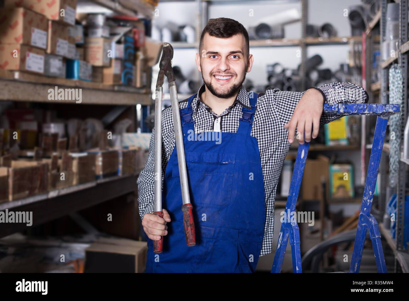 Smiling male worker showing various instruments at workshop Stock Photo ...