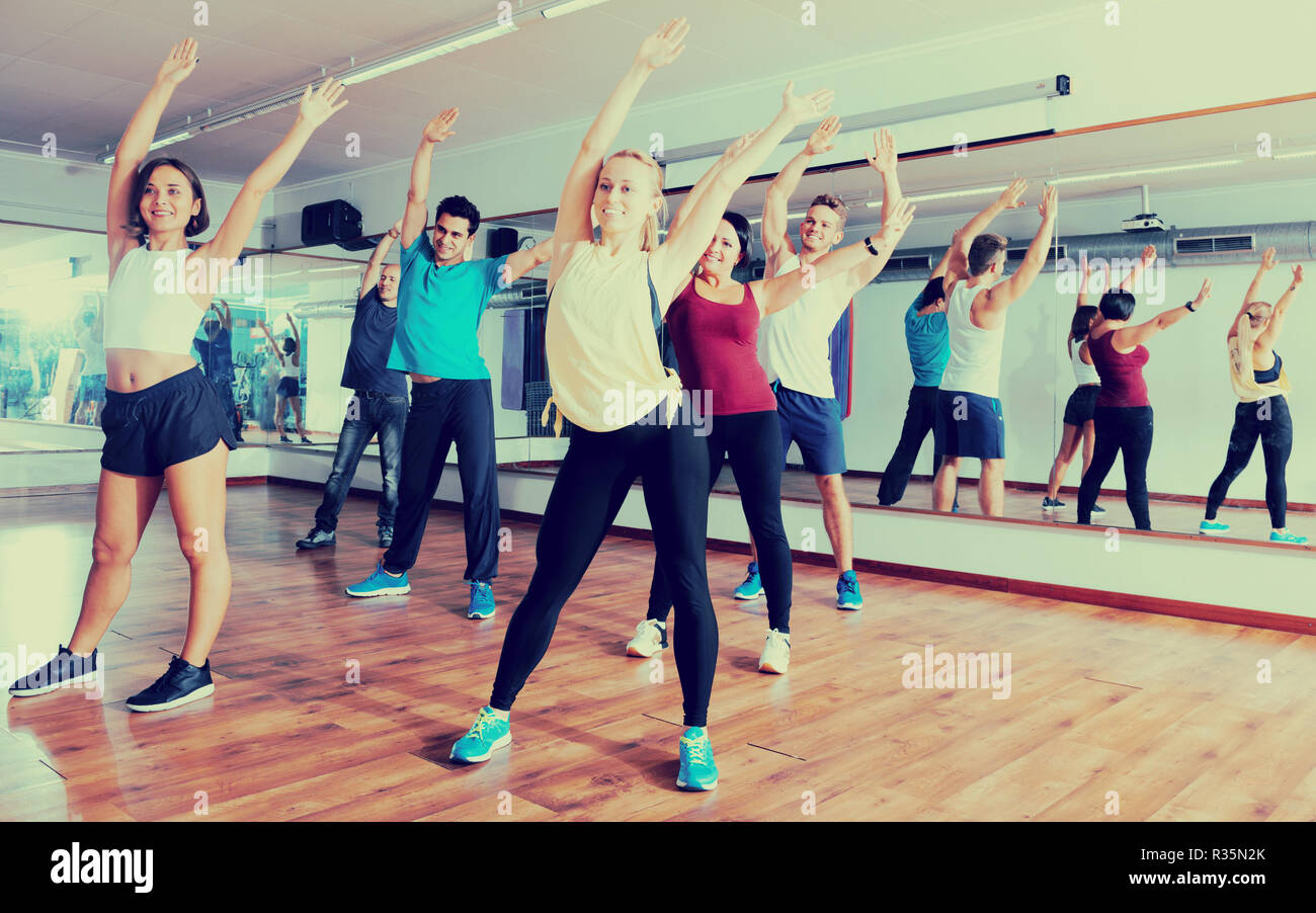 Positive people exercising zumba elements together in dancing class ...