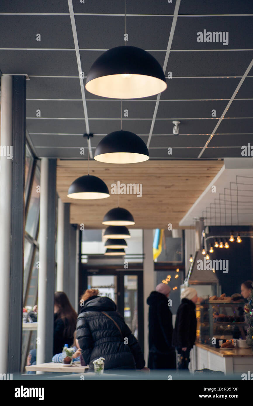 People in a cafe with a black ceiling and lights on Stock Photo - Alamy