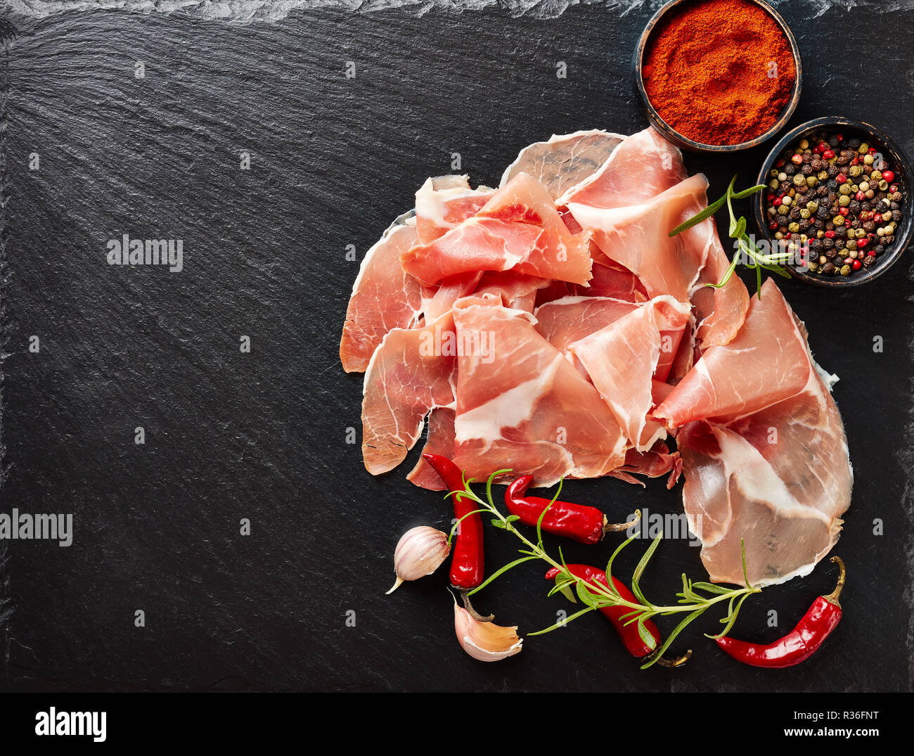 spanish dry-cured ham, jamon curado thinly sliced and served on a black ...