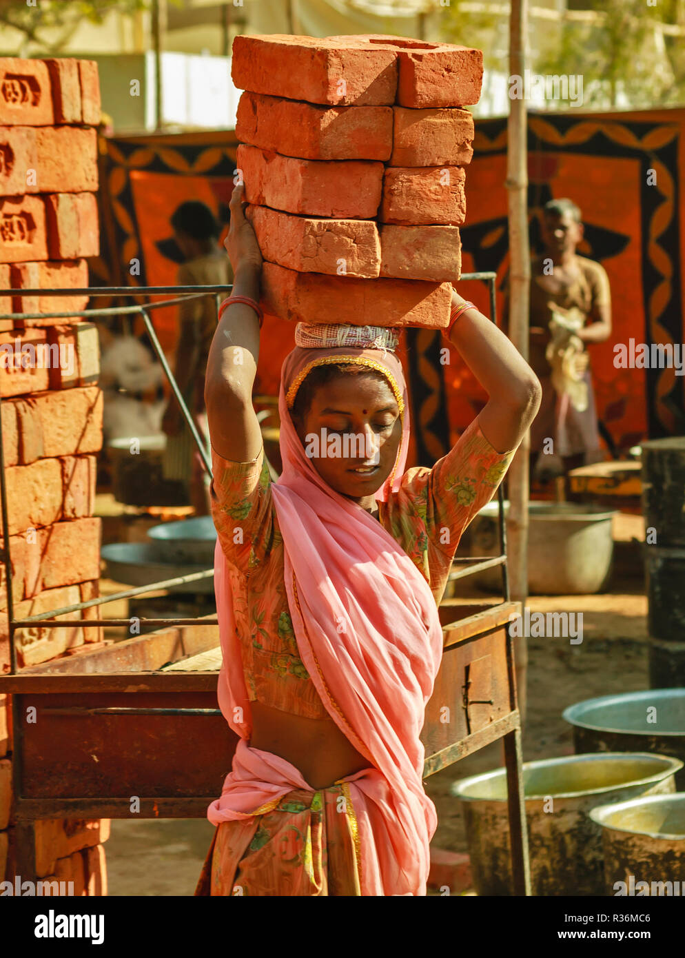 RAJASTHAN INDIA YOUNG WOMAN CARRYING A LOAD OF TEN HOUSE BRICKS ON HER ...