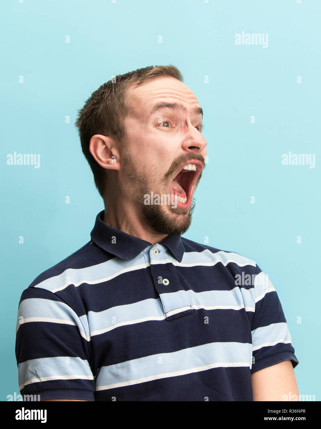 The surprised and astonished young man screaming with open mouth ...