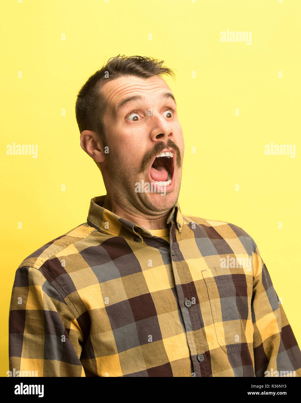 The surprised and astonished young man screaming with open mouth ...