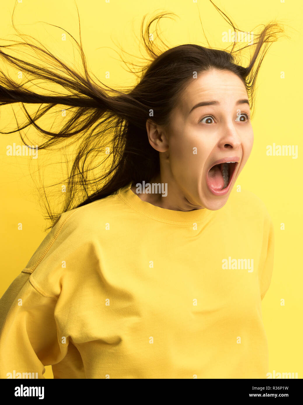 The surprised and astonished young woman screaming with open mouth ...