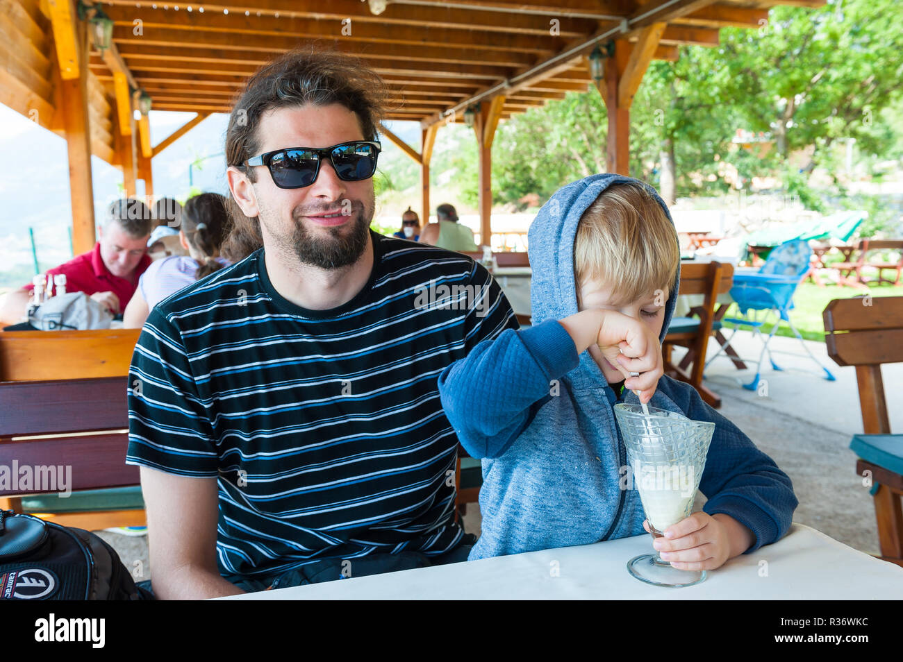 Four year old boy sitting next to his father and eating ice cream in a ...