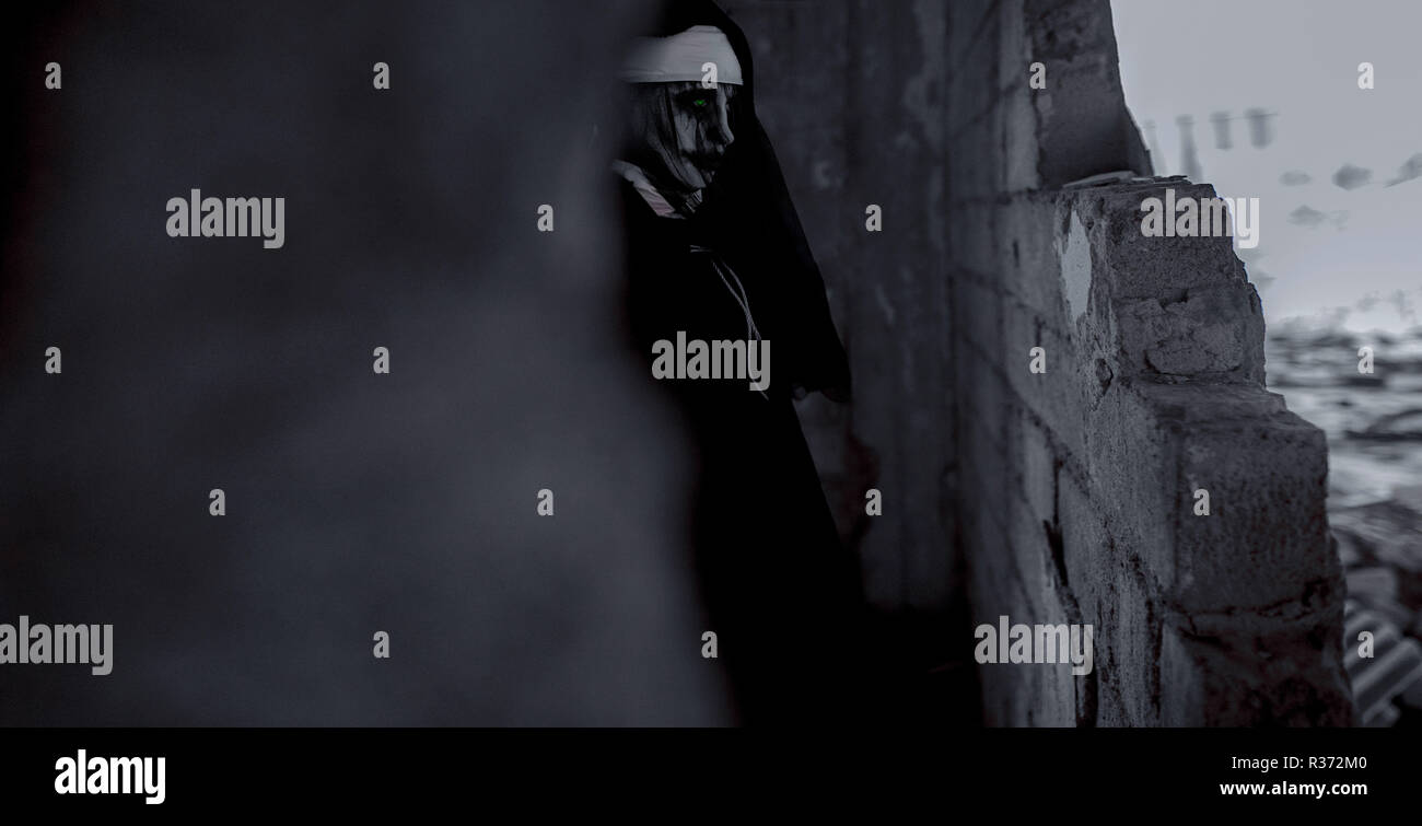 Woman is standing in a darkness dressed in a black hooded cloak in an ...