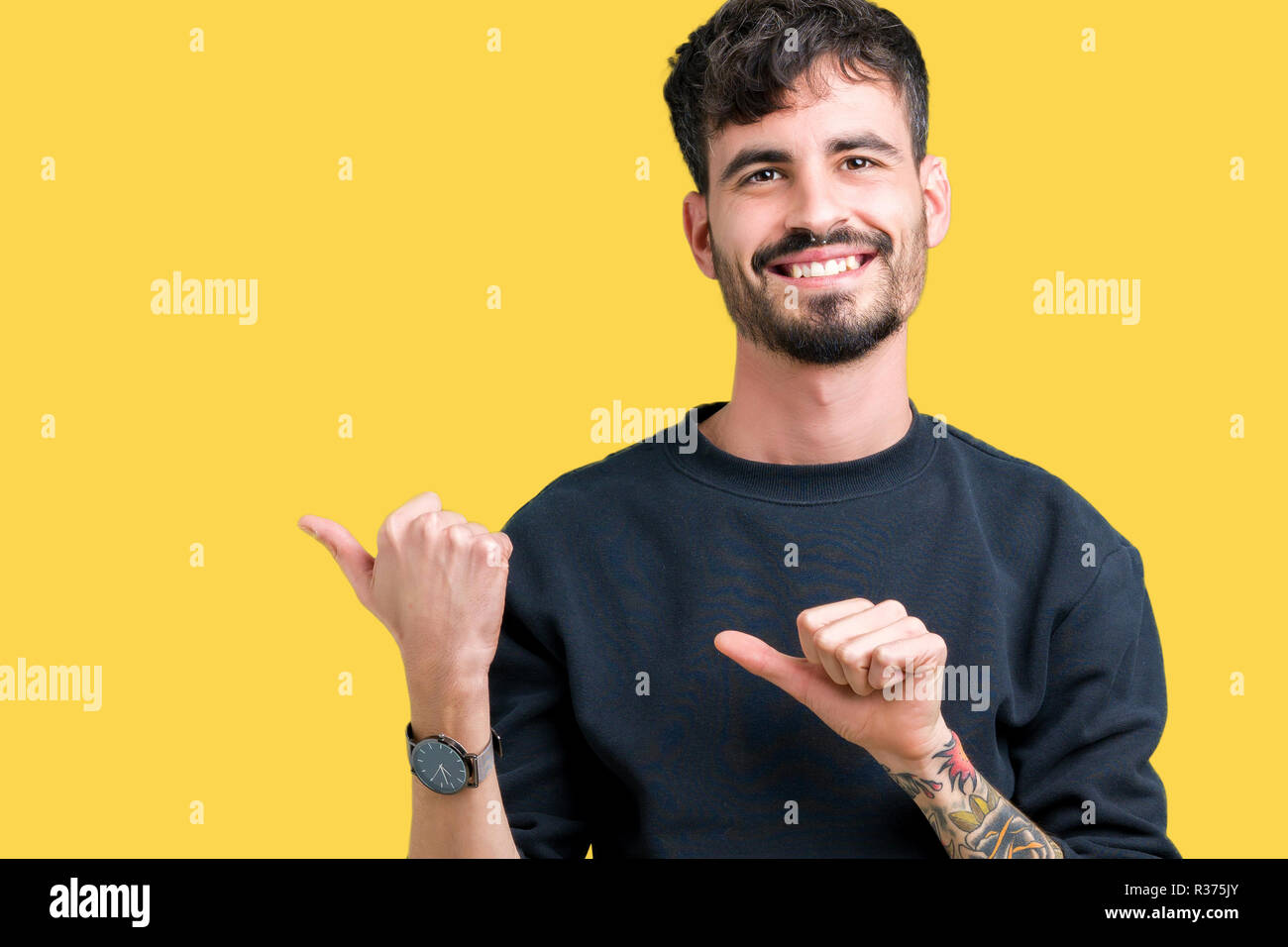 Young handsome man over isolated background Pointing to the back behind ...