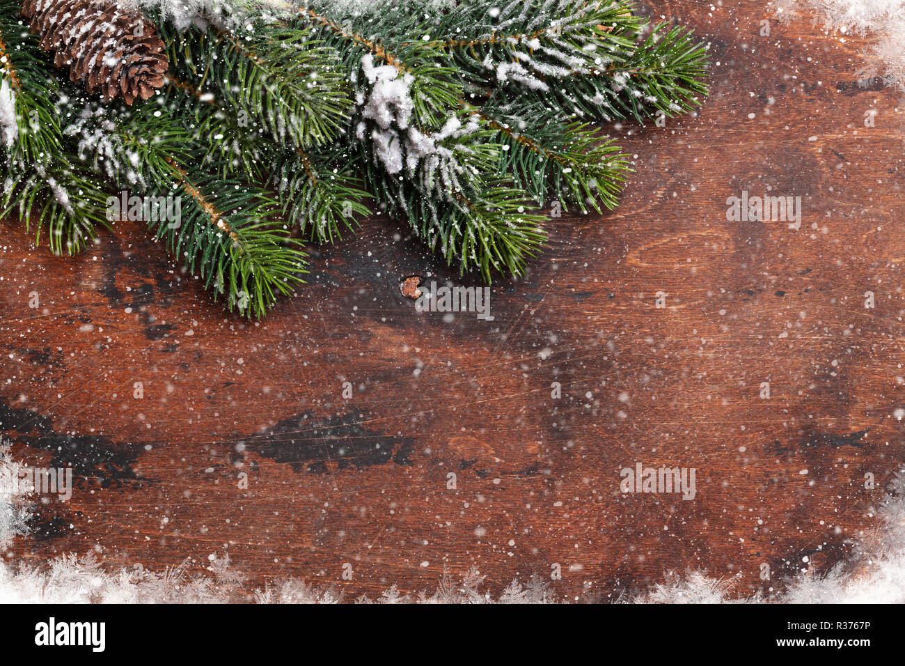 Christmas fir tree branch covered by snow on wooden background. Top ...