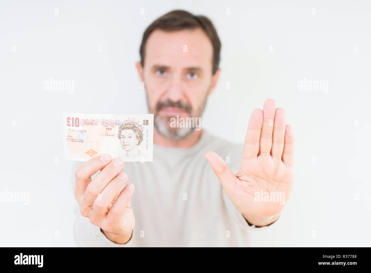 Senior man holding ten pounds bank note over isolated background with ...