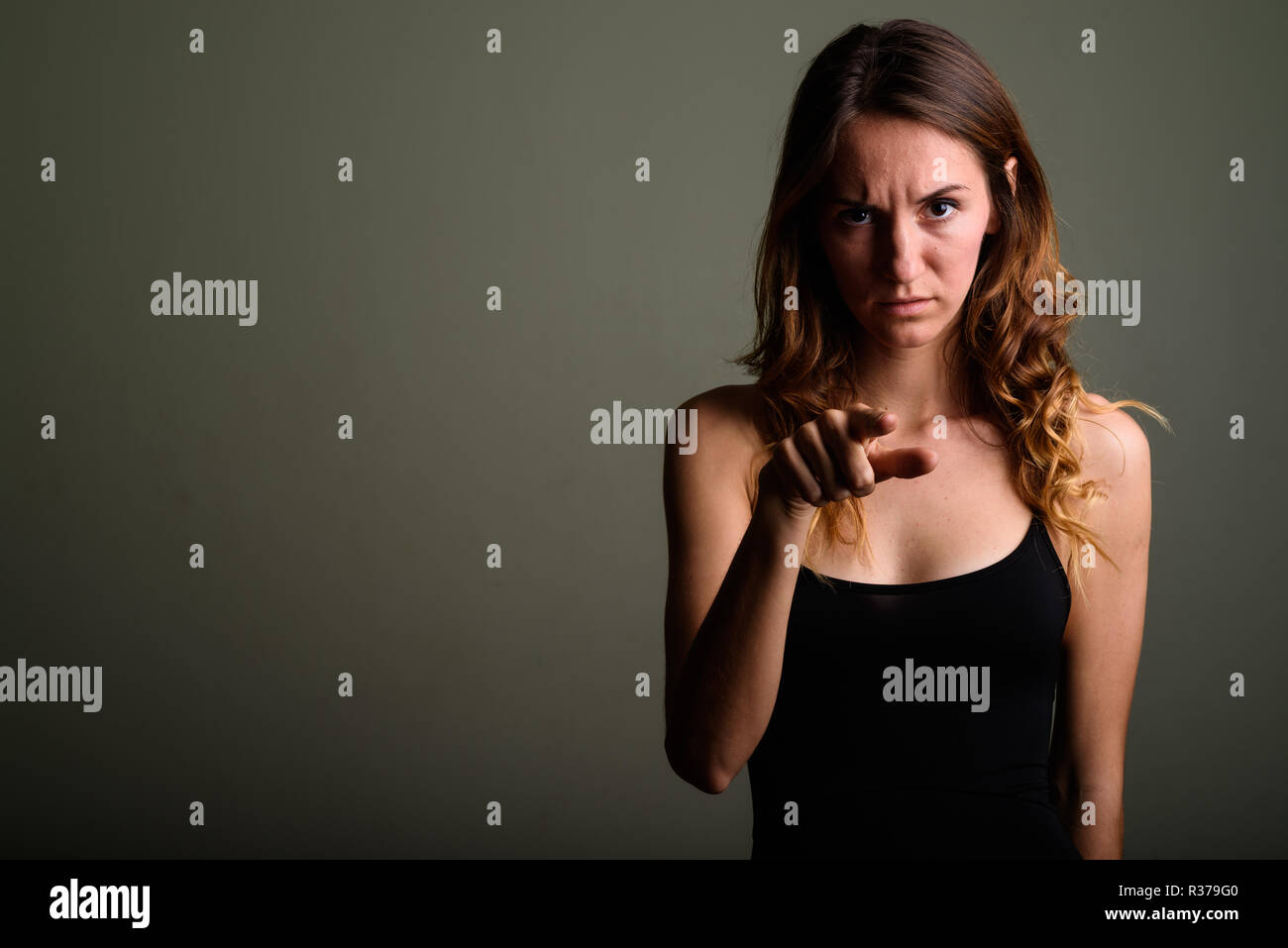 Young beautiful woman wearing sleeveless top against colored bac Stock ...