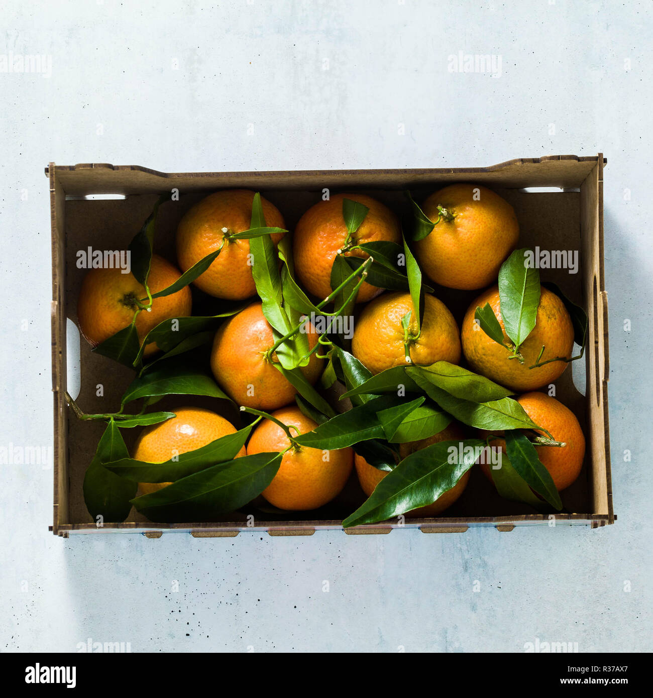 Fresh mandarin oranges fruit or tangerines with leaves in wooden box ...