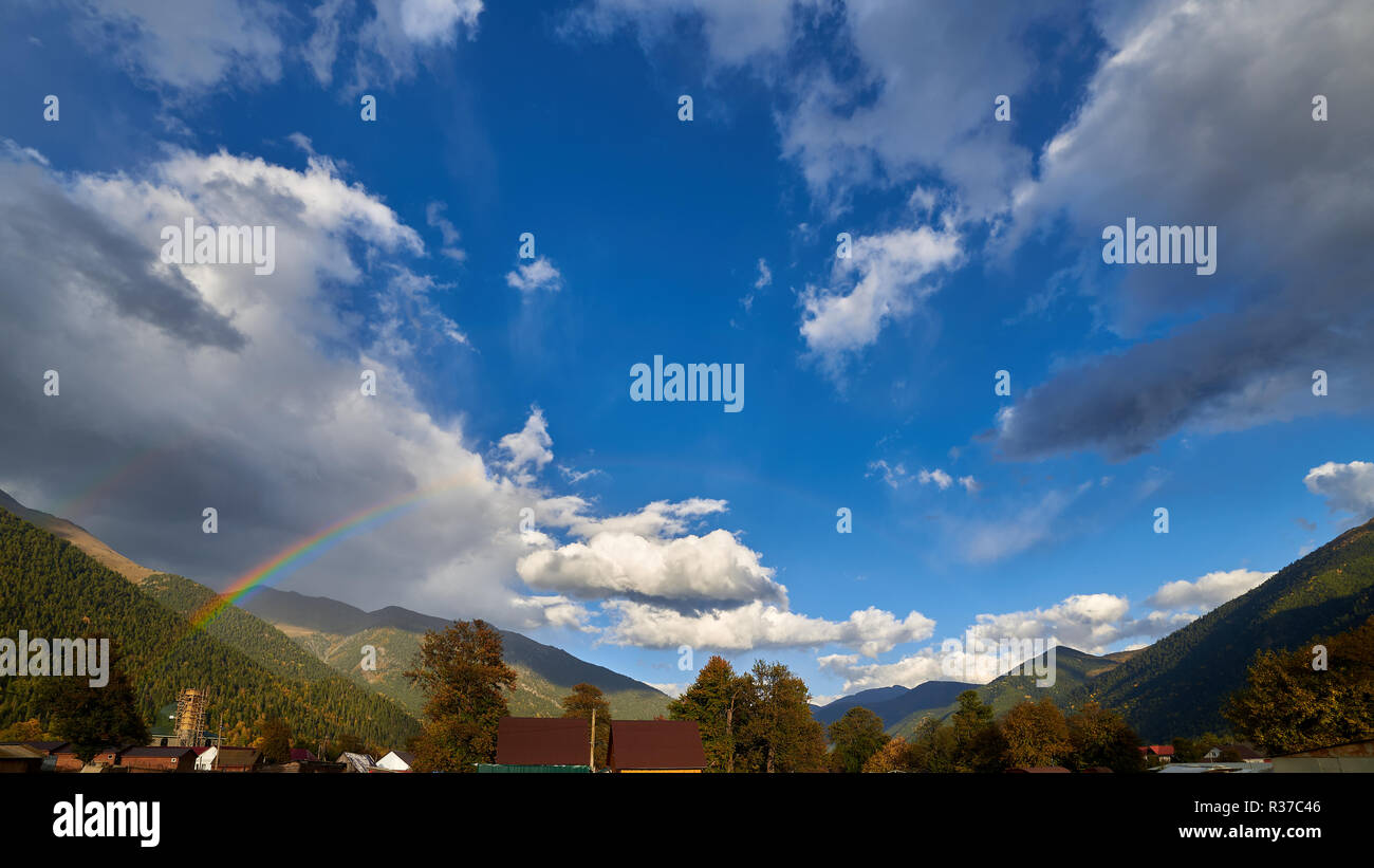 Rainbow on a background of mountains, blue sky and clouds Stock Photo ...