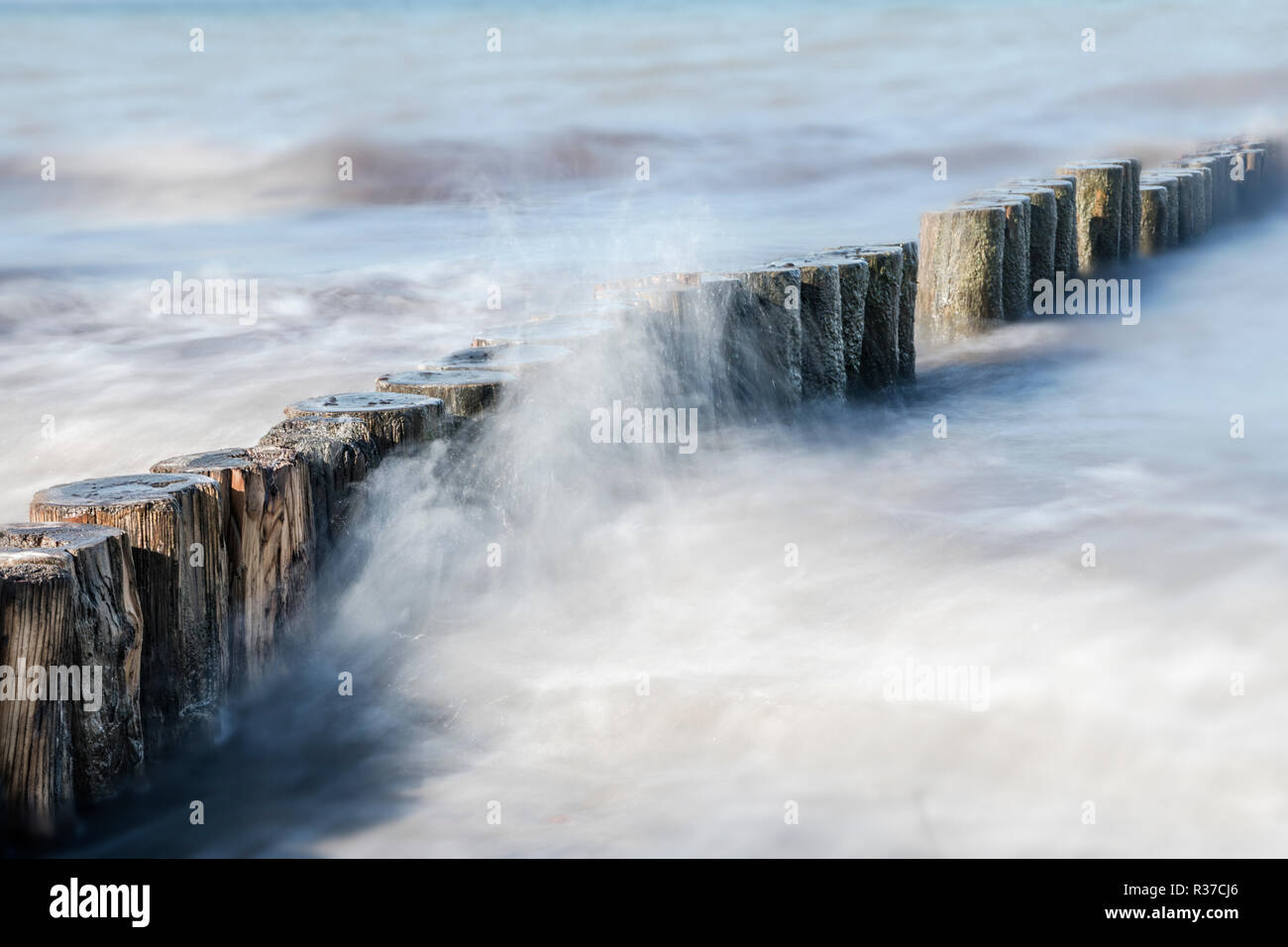 wooden groynes in the spray of the sea, smooth water by long exposure ...