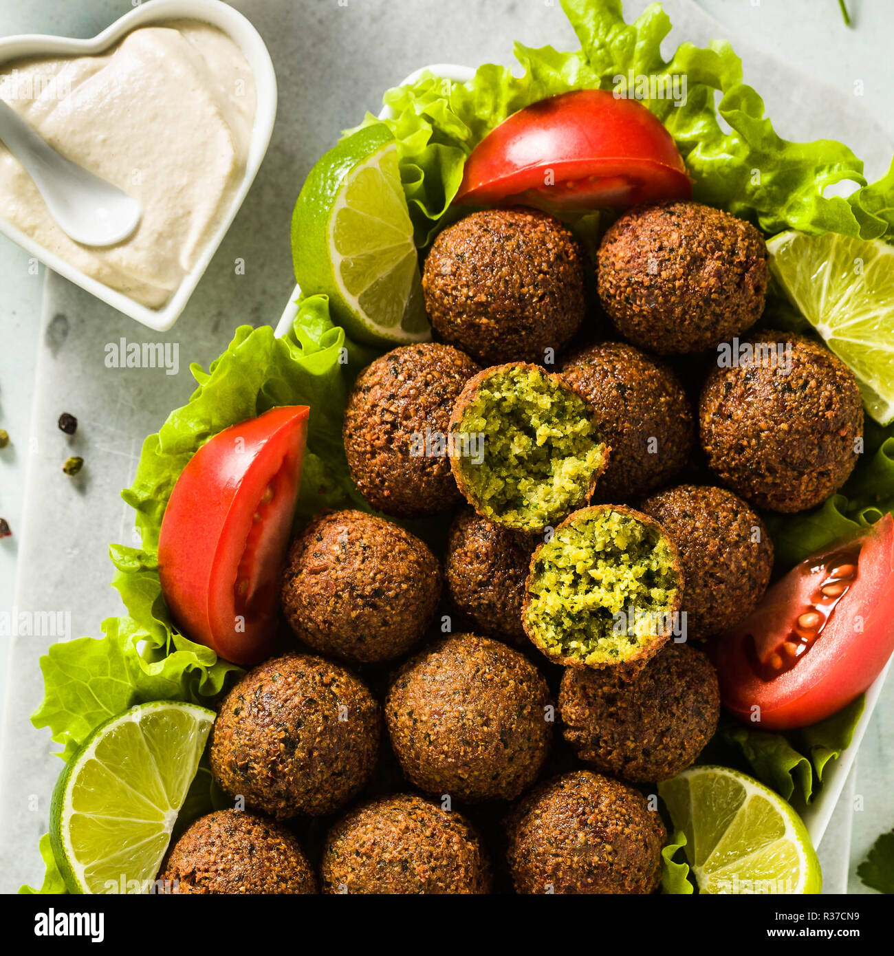 vegan falafel with cashew cheese sauce on a table with chopped tomatoes ...
