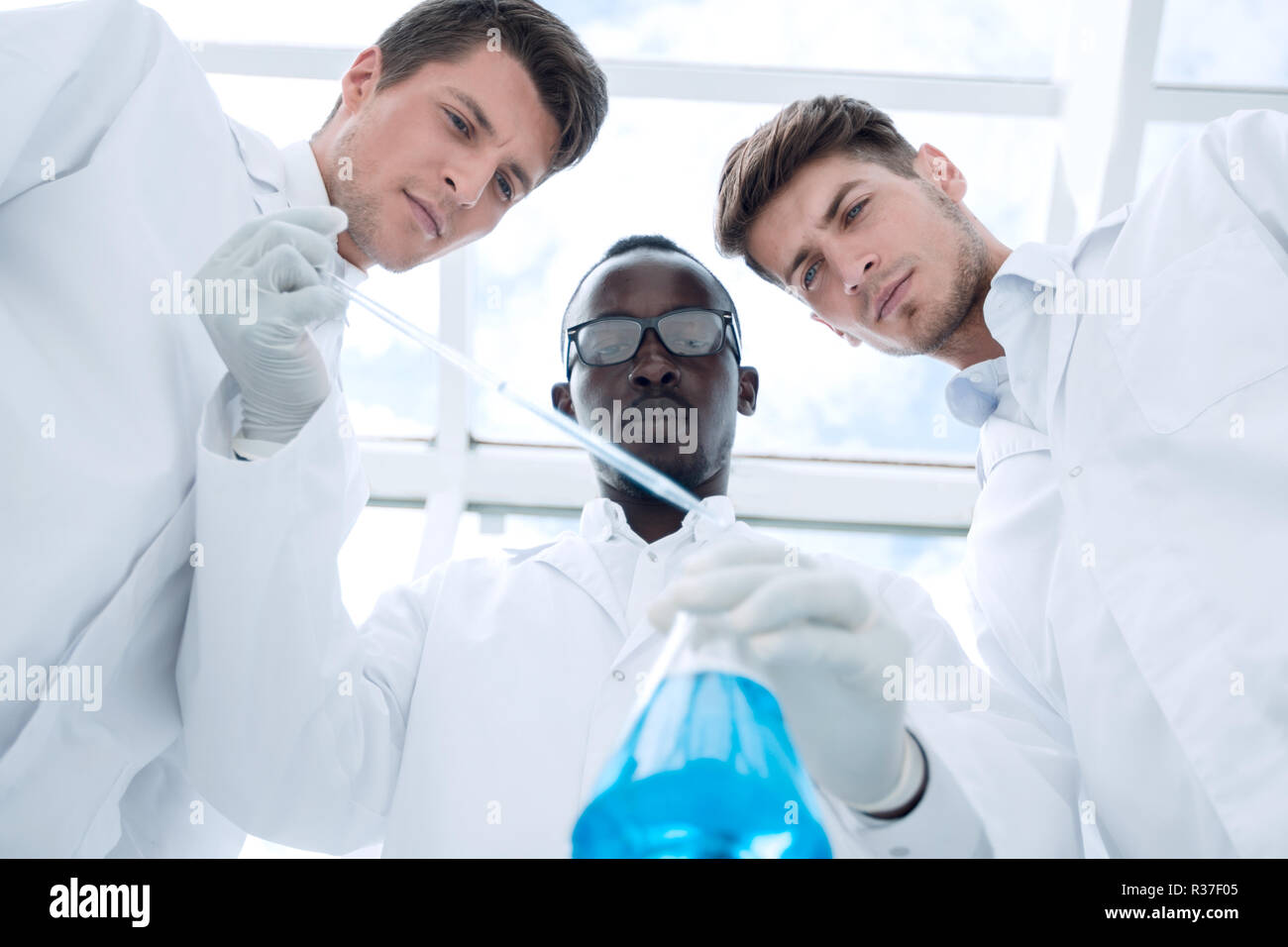 group of scientists examines the liquid in the flask Stock Photo - Alamy