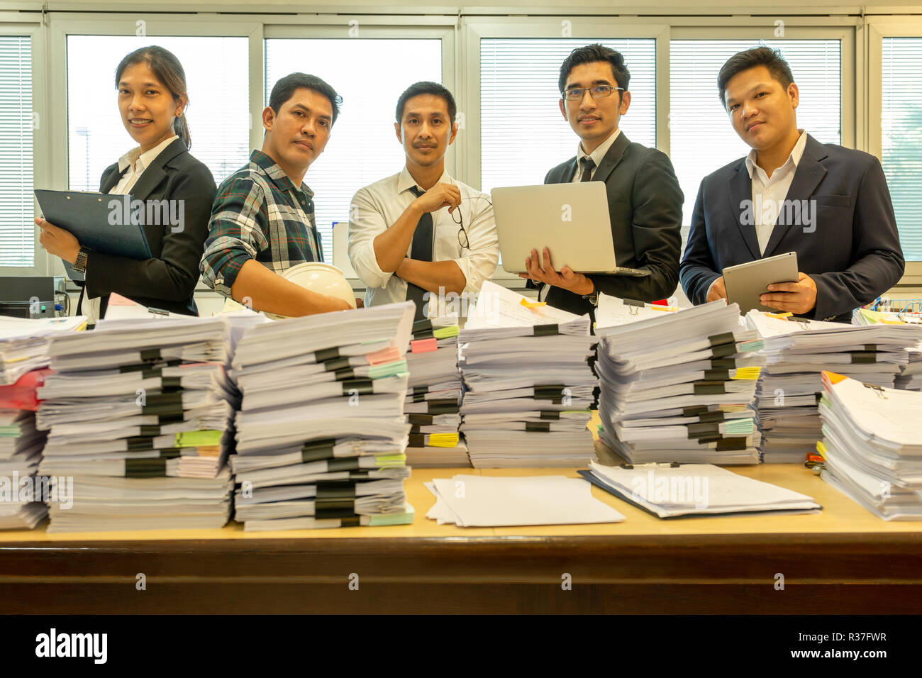 Group of business people standing behild of pile paperwork on table in ...