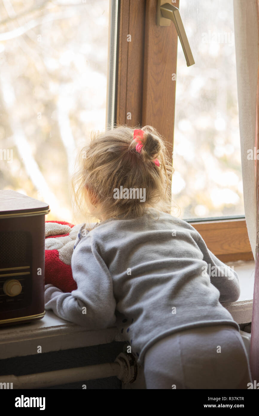 Kid looks out the window, view from the back Stock Photo - Alamy