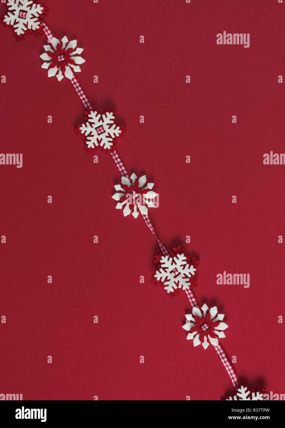 red felt decorative christmas garland on red background Stock Photo - Alamy
