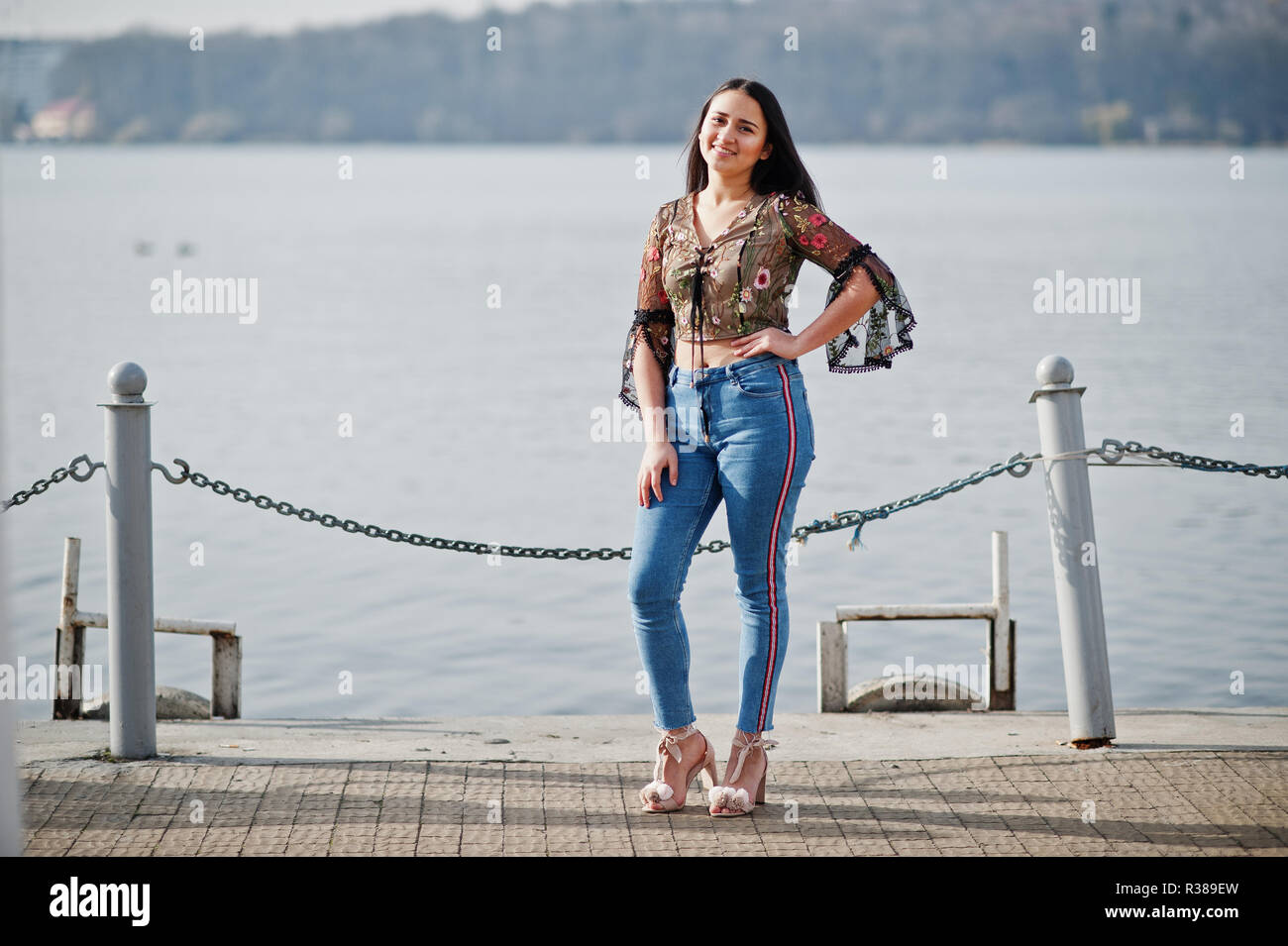 Pretty latino model girl from Ecuador wear on jeans posed against lake ...