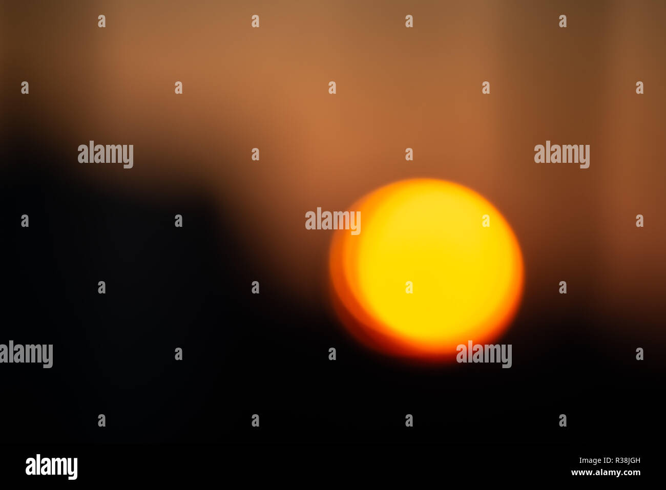 red sunset with sun setting down behind large electricity power line ...