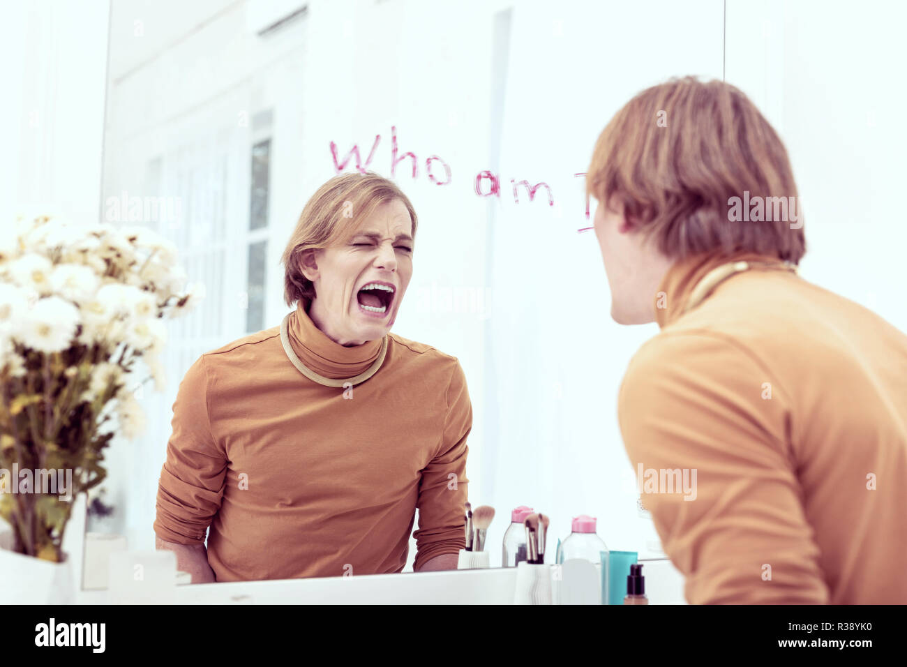 Upset transgender yelling at himself in the mirror Stock Photo - Alamy