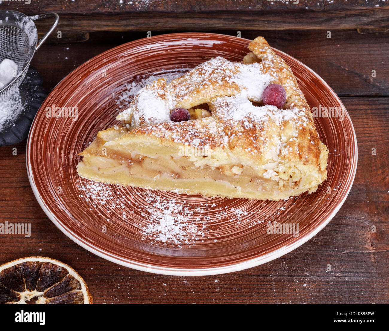 triangular slice of apple pie puff pastry on a round brown plate Stock ...