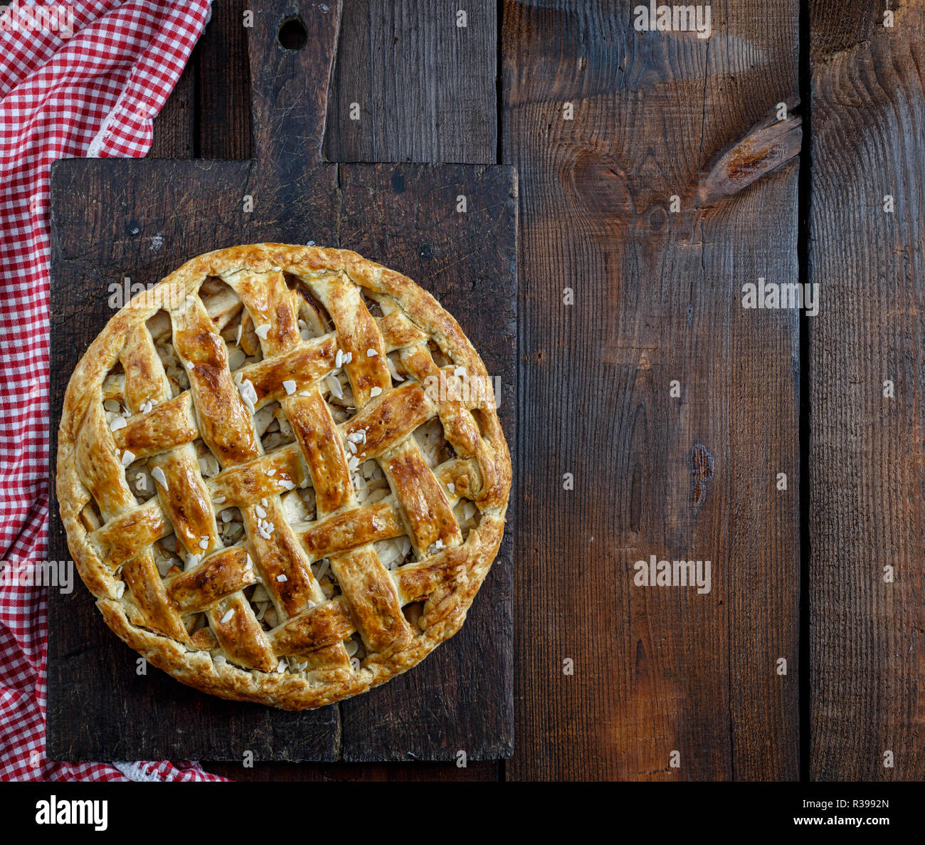Baked whole round apple pie on a rectangular old brown board, wooden ...