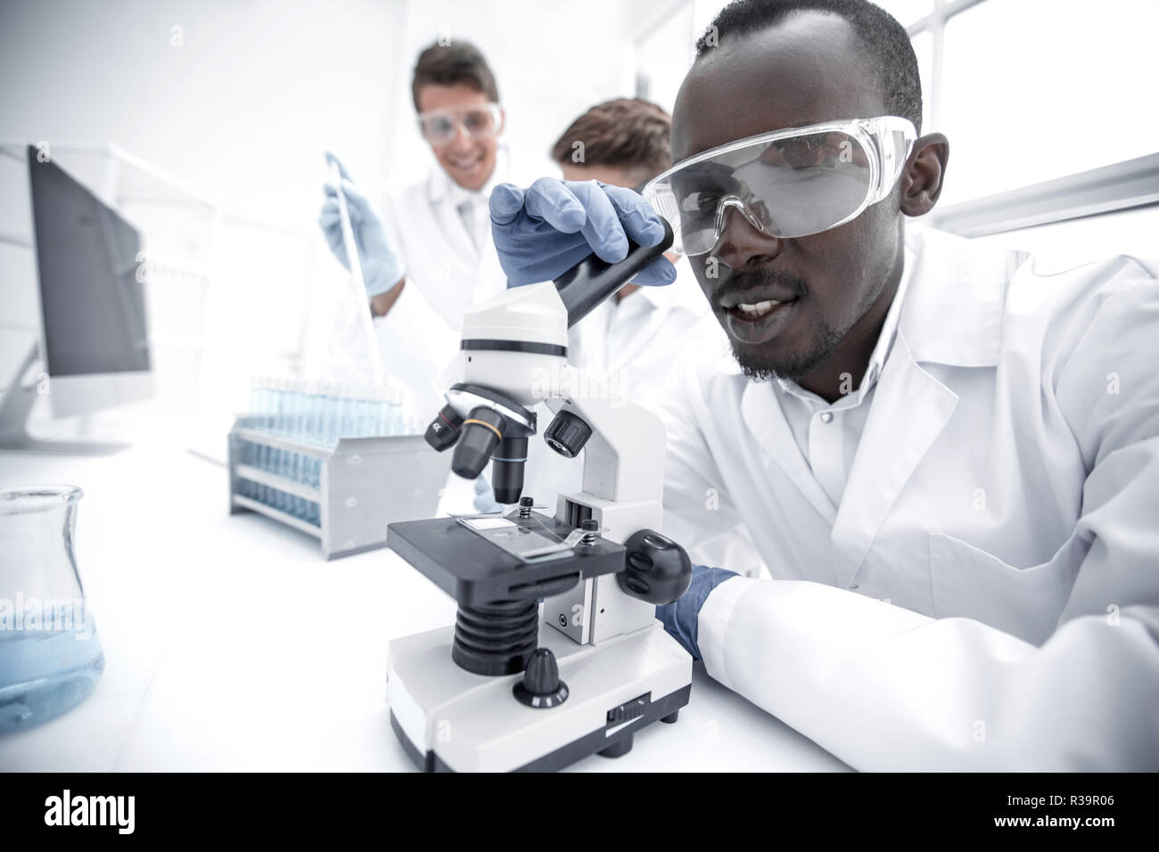 Scientists observing sample in microscope hi-res stock photography and ...