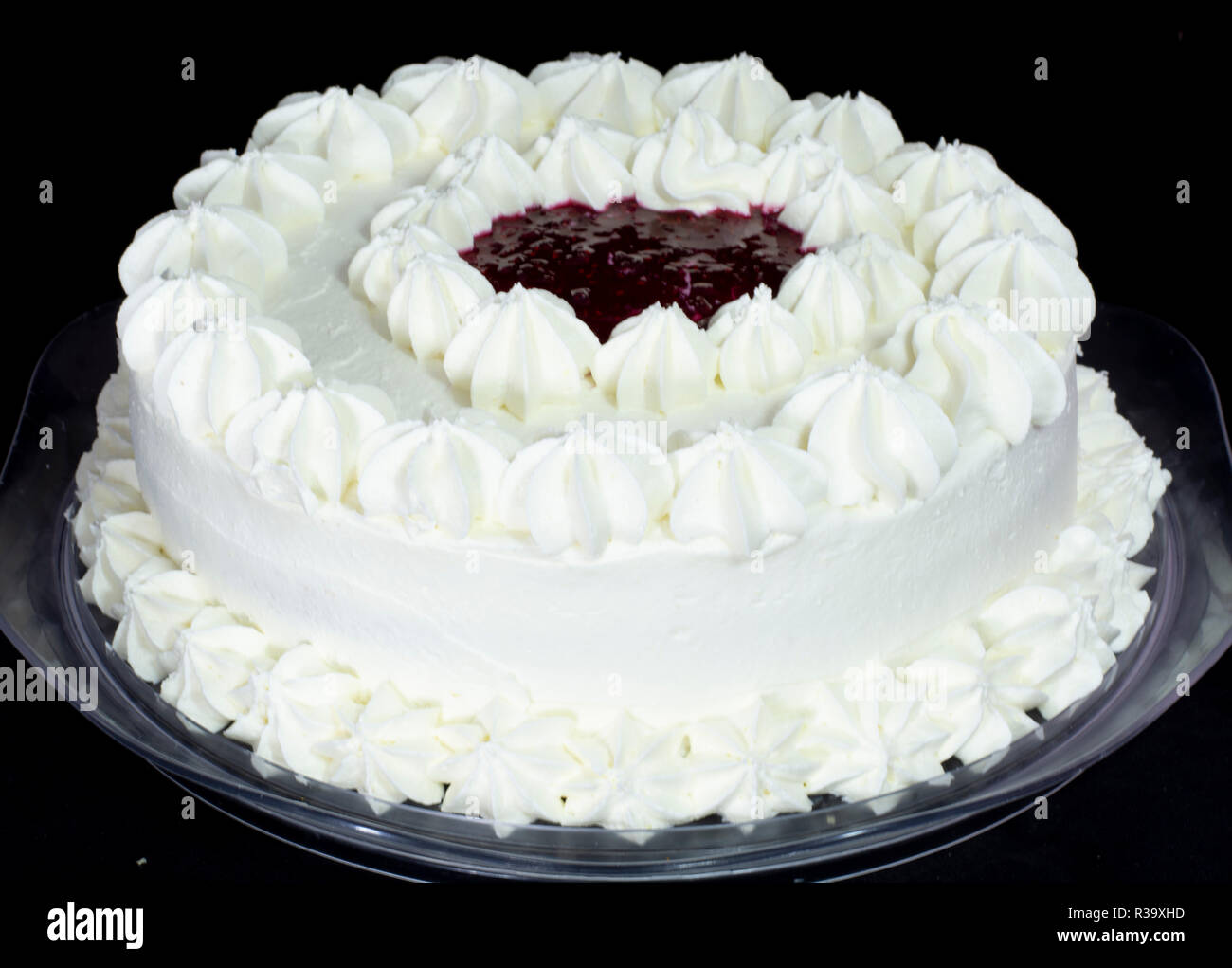 White cream cake with raspberry dressing on it with isolated black ...