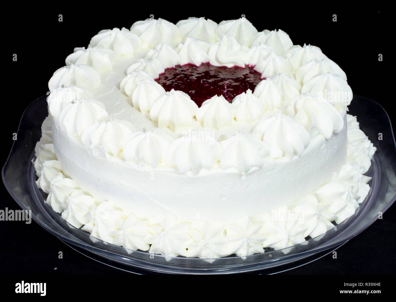 White cream cake with raspberry dressing on it with isolated black ...