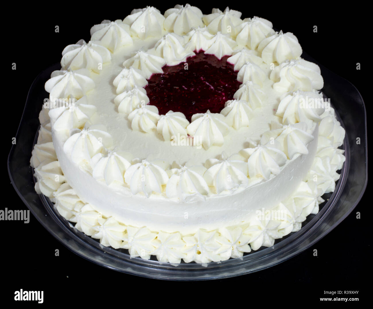 White cream cake with raspberry dressing on it with isolated black ...