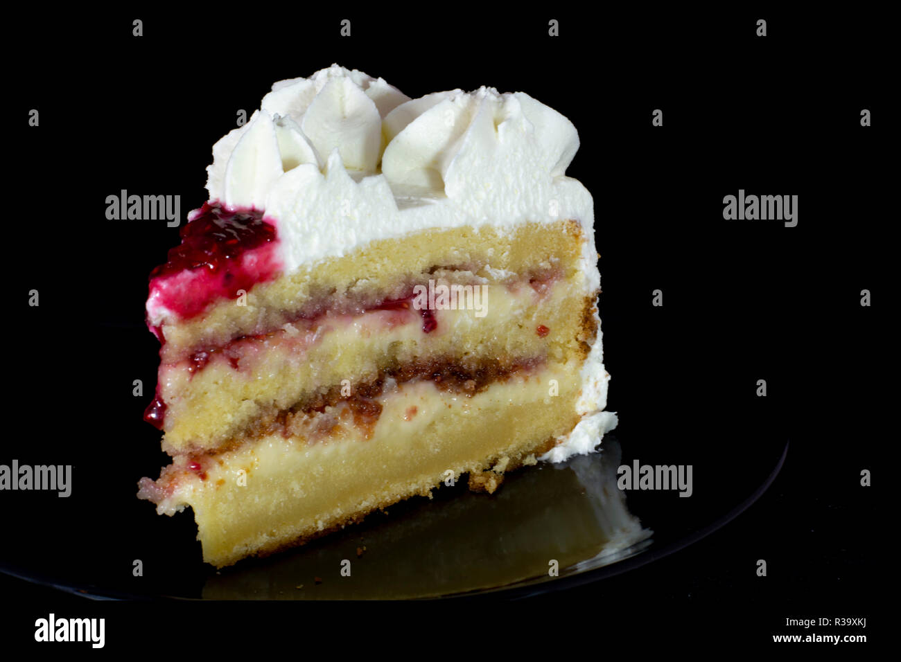White cream cake with raspberry dressing on it with isolated black ...