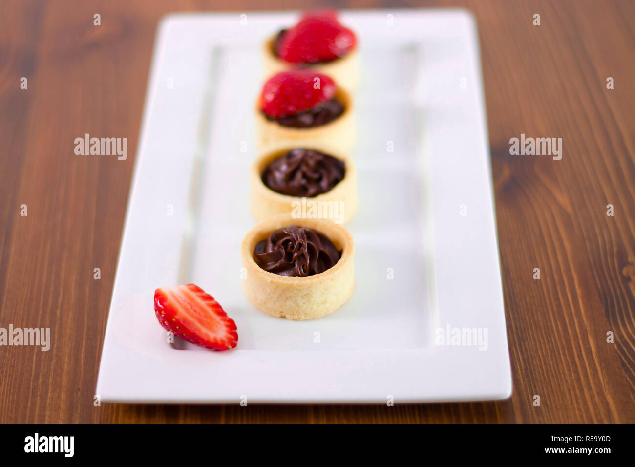 Small chocolate tarts with fresh strawberry on wood Stock Photo - Alamy