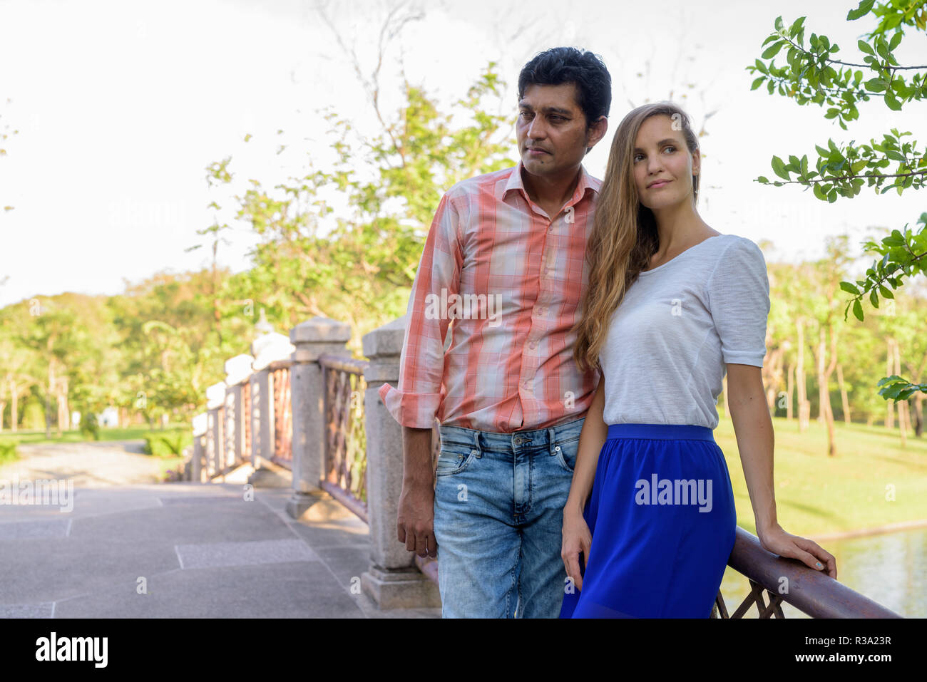 Multi ethnic couple thinking together and in love on the bridge Stock ...