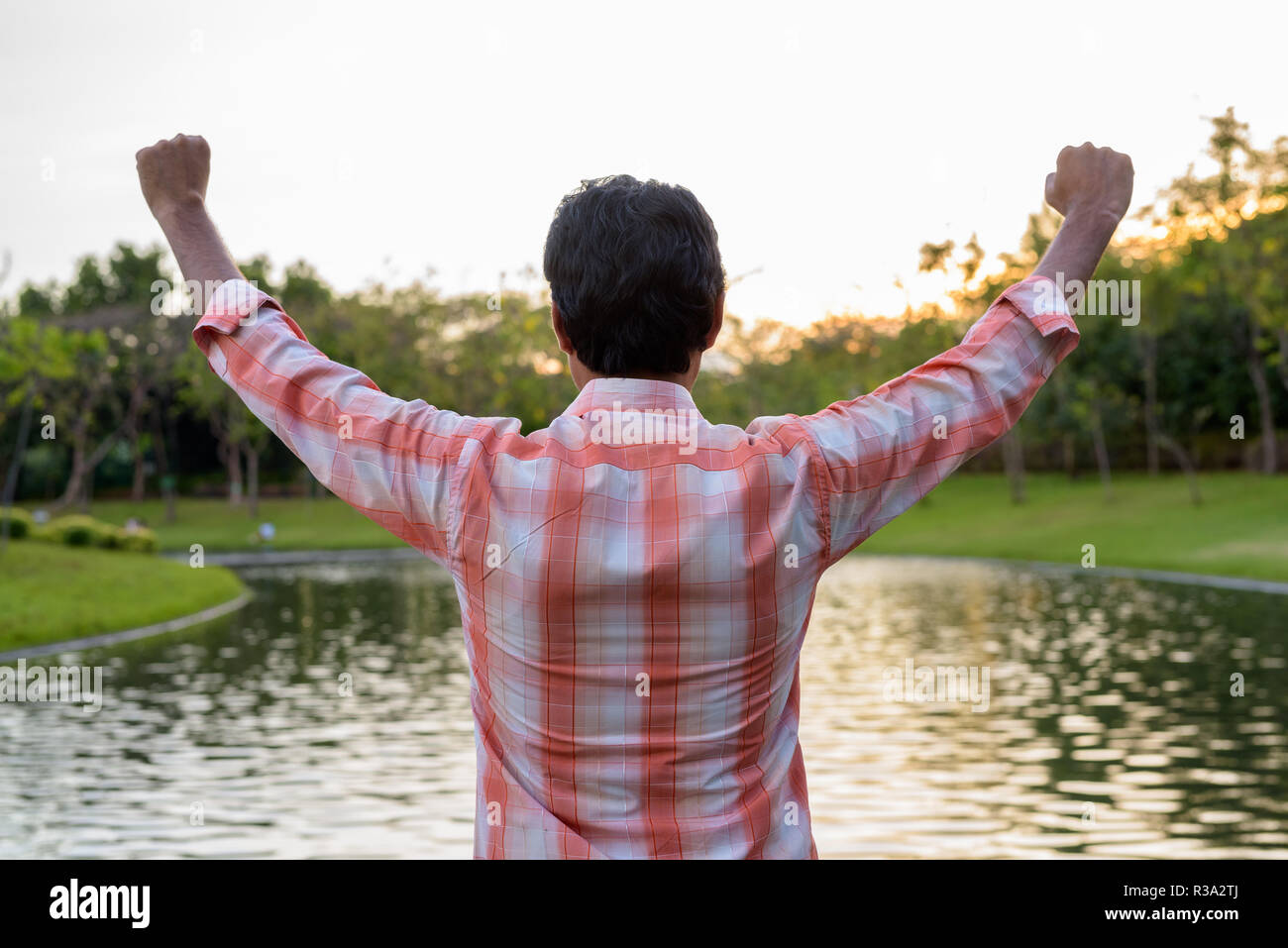 Indian man raising both his arms against scenic view of the lake Stock ...