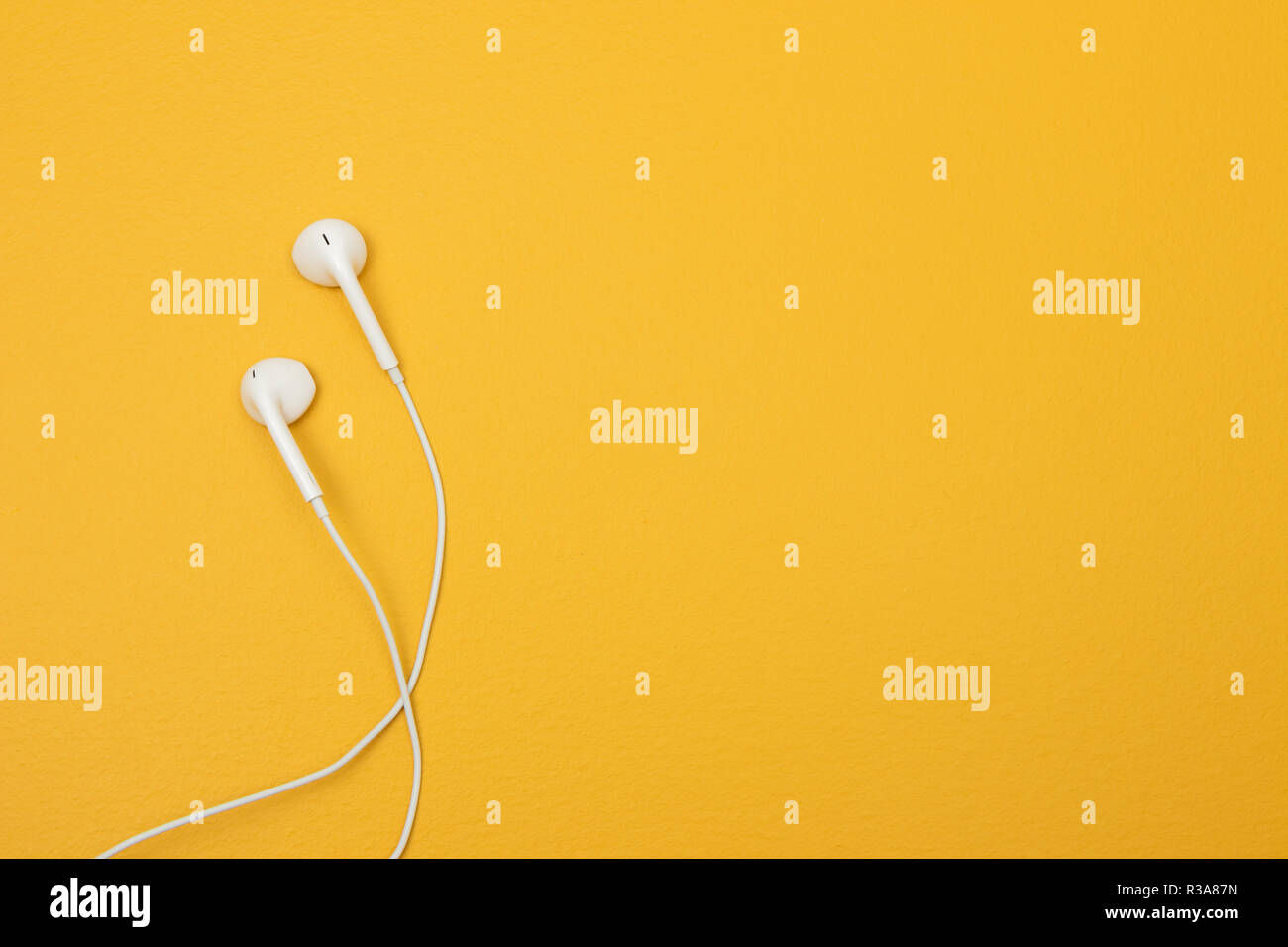 White earphones on yellow background, with space for text on the right ...