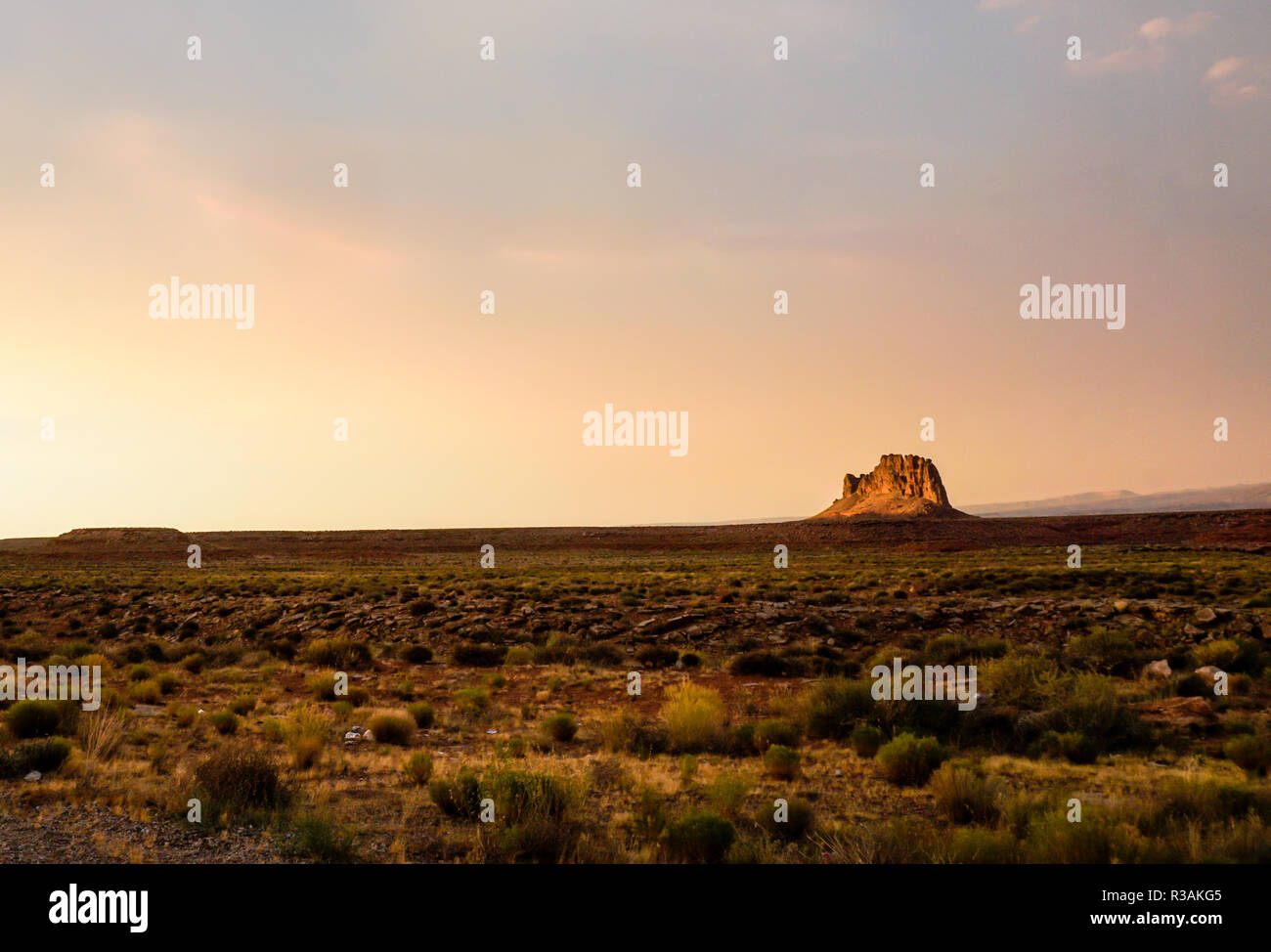 colorful desert sunset over a single rock butte or mesa rock formation ...