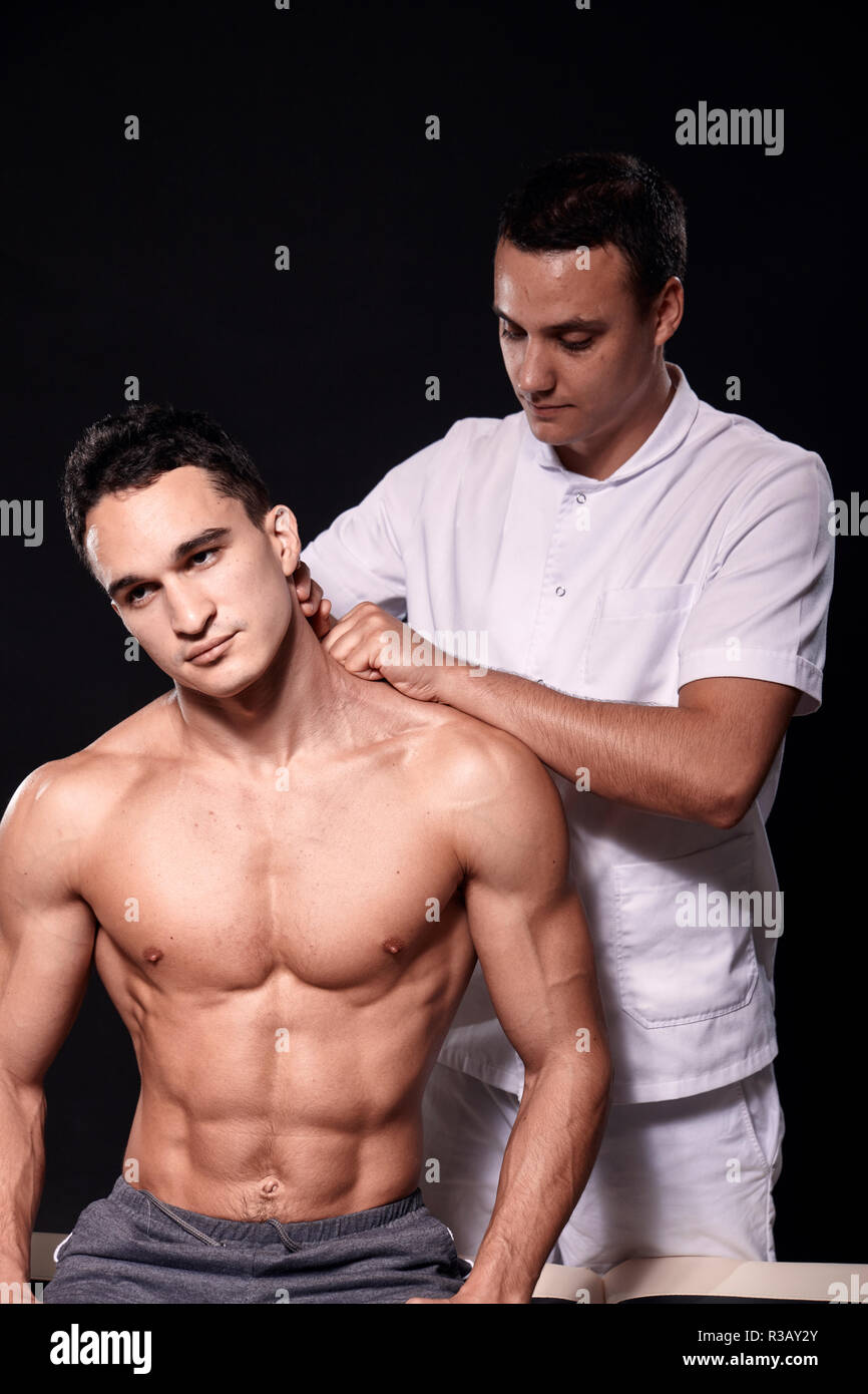 two young man, 20-29 years old, sports physiotherapy indoors in studio ...
