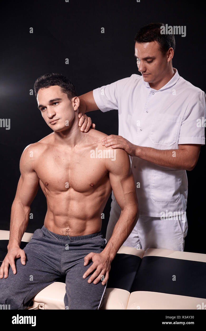 two young man, 20-29 years old, sports physiotherapy indoors in studio ...