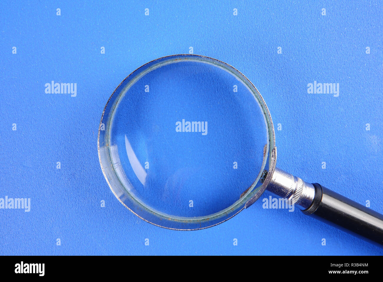 Hand holding magnify glass over a blue background Stock Photo - Alamy