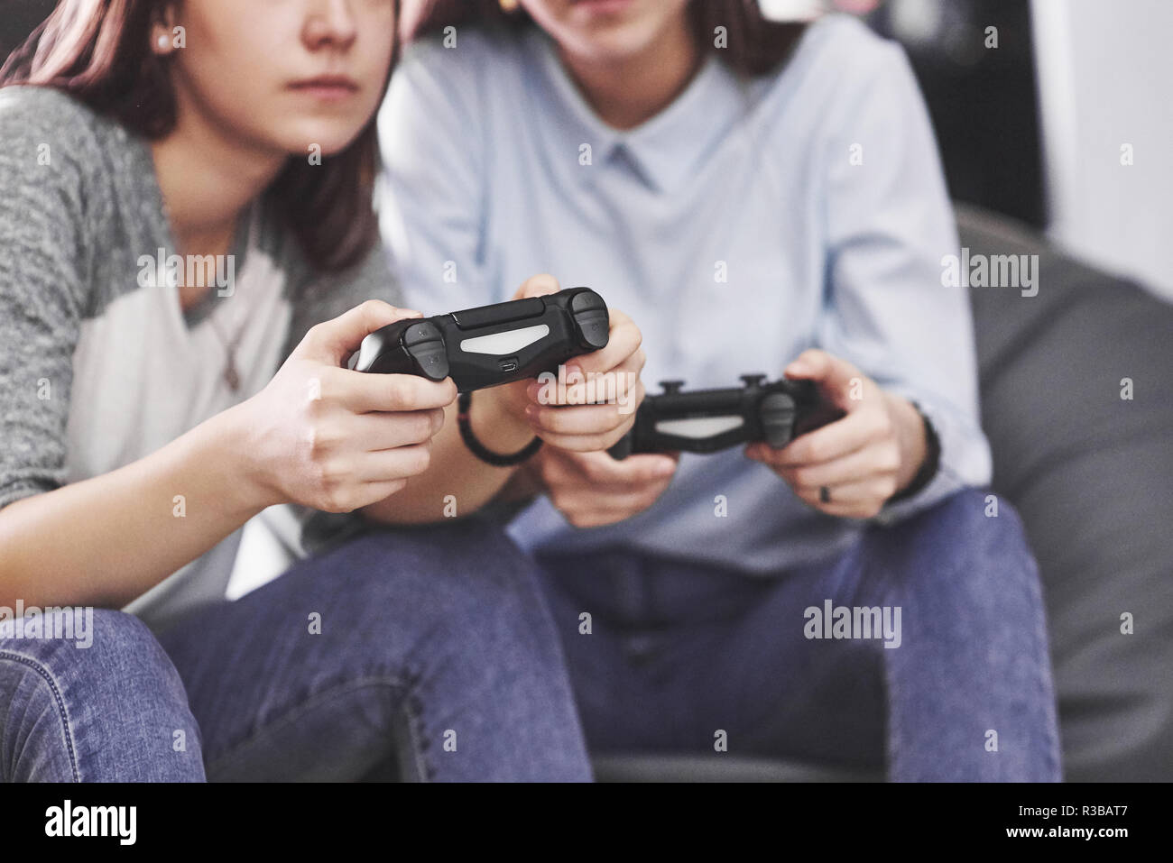 Twin sister sisters play on the console. Girls hold joysticks in their ...