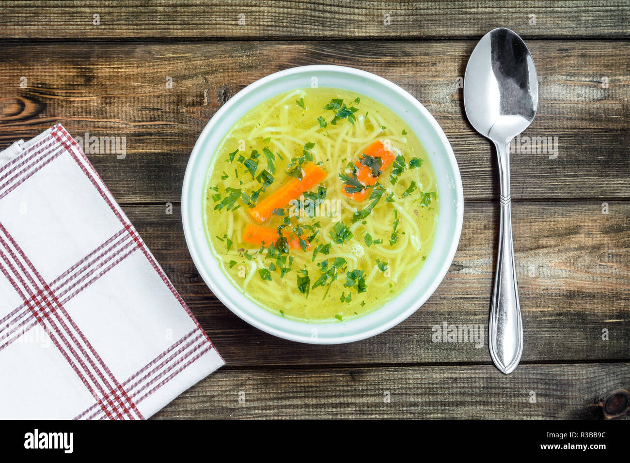 Chicken broth soup with noodles on a wooden table Stock Photo - Alamy